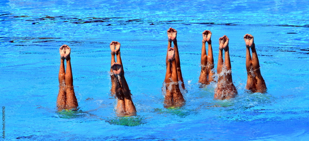 Synchronized Swimmers point up out of the water in action. Synchronized ...