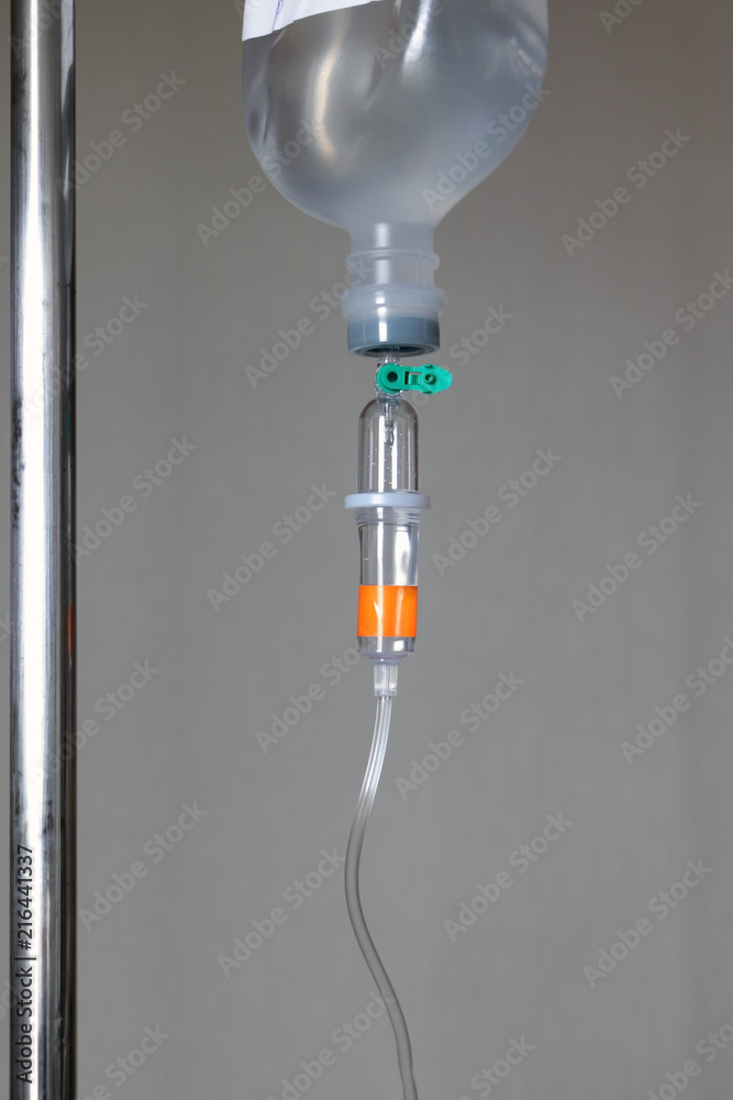 A stand with drip bag against wall. Close up saline solution drip for ...