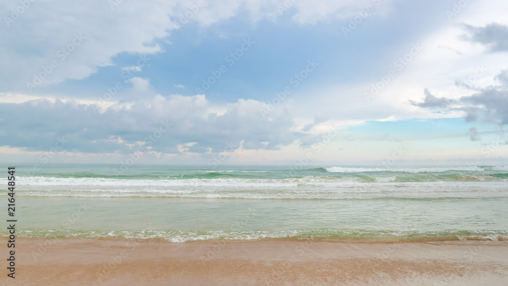 A front view of a beach with the sand and a green sea with small waves ...