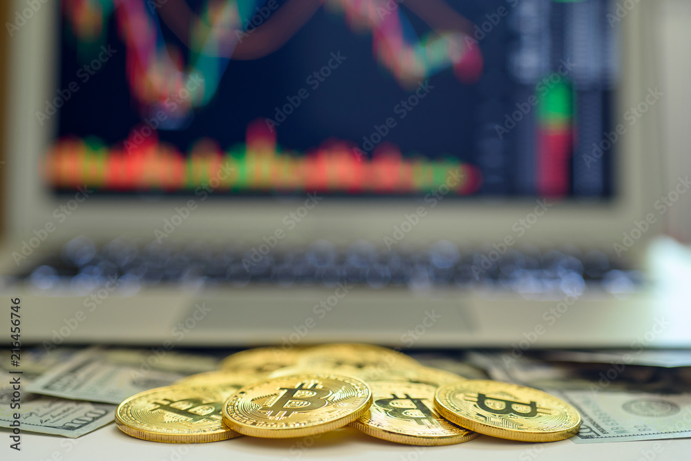 Gold bitcoins and dollar bills appearing from above a laptop with stock ...