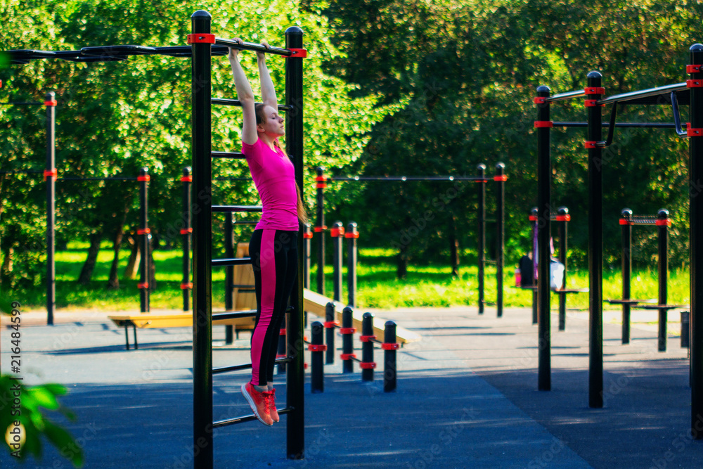Hanging on a vertical metal ladder. Girl in pink sportswear doing ...