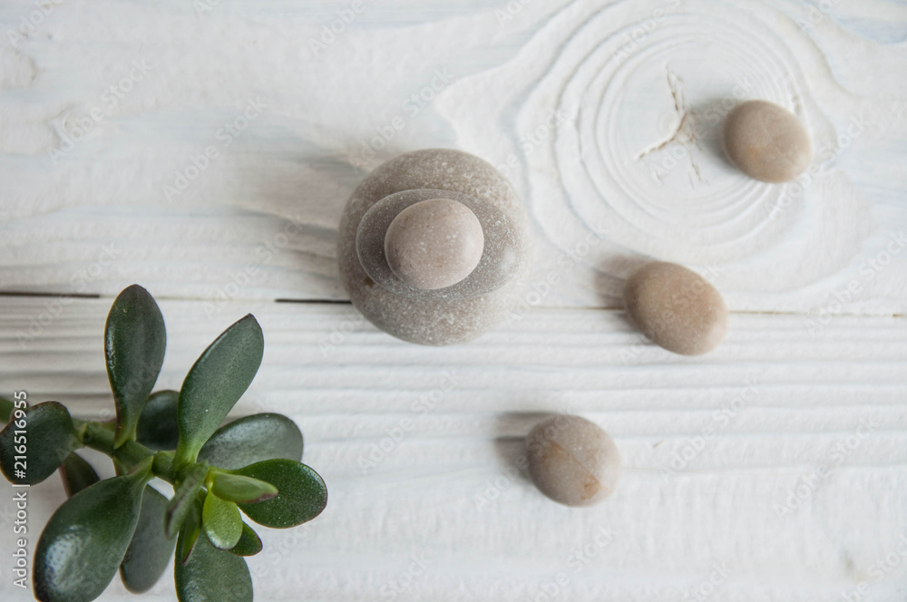 Pyramids of white zen stones with green leaves on white background ...