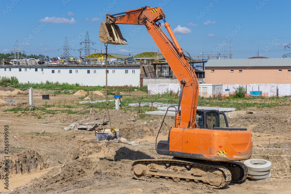 Excavator moves a concrete ring for a sewer well Stock Photo | Adobe Stock