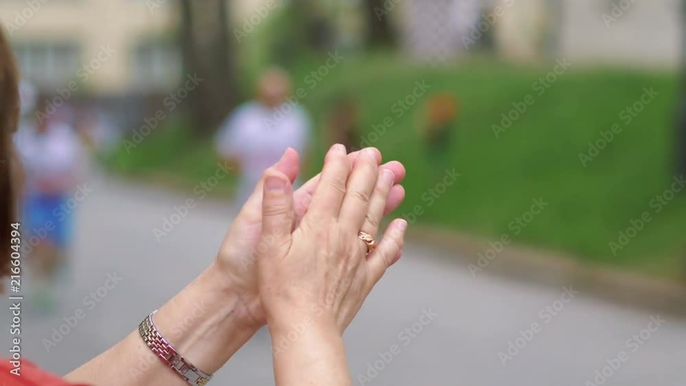 Senior woman cheering runners and clapping hands in 4k slow motion ...