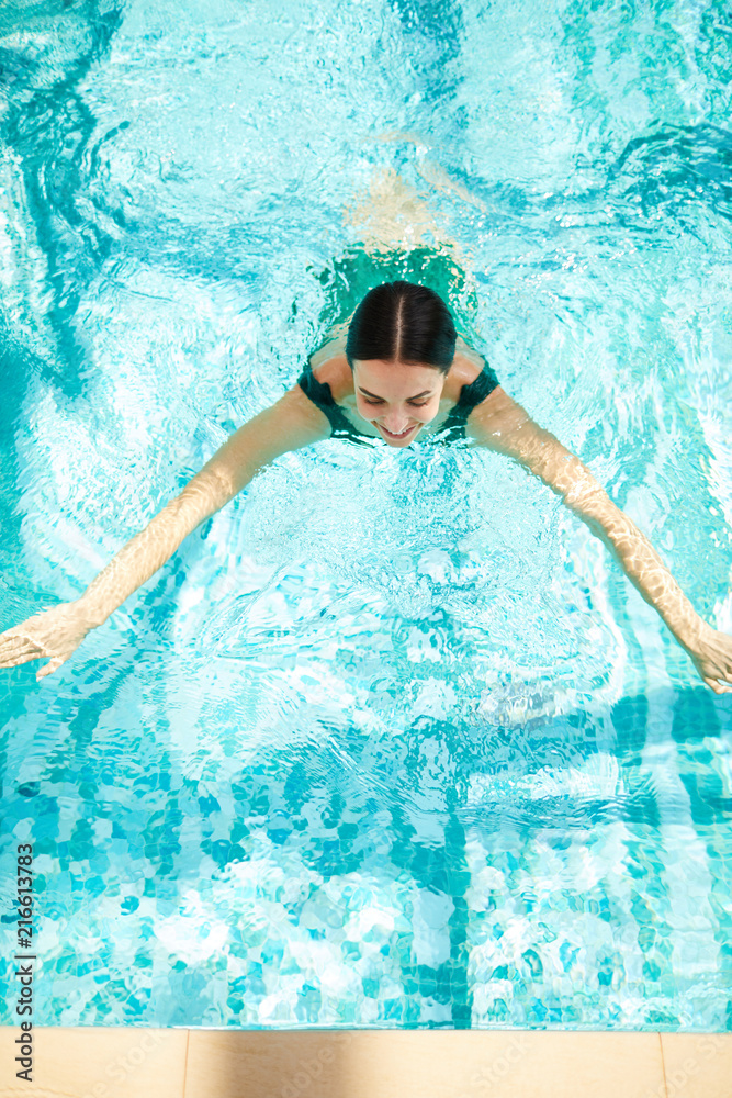Overview of active girl swimming in transparent water and enjoying day ...