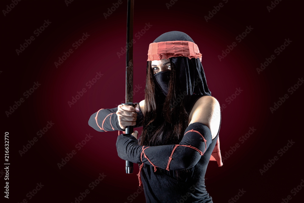Beautiful samurai woman warrior with a sword in studio on red dark ...