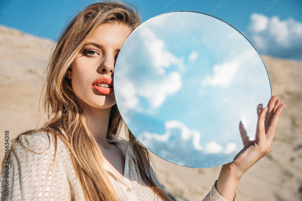attractive elegant model holding round mirror with reflection of cloudy ...