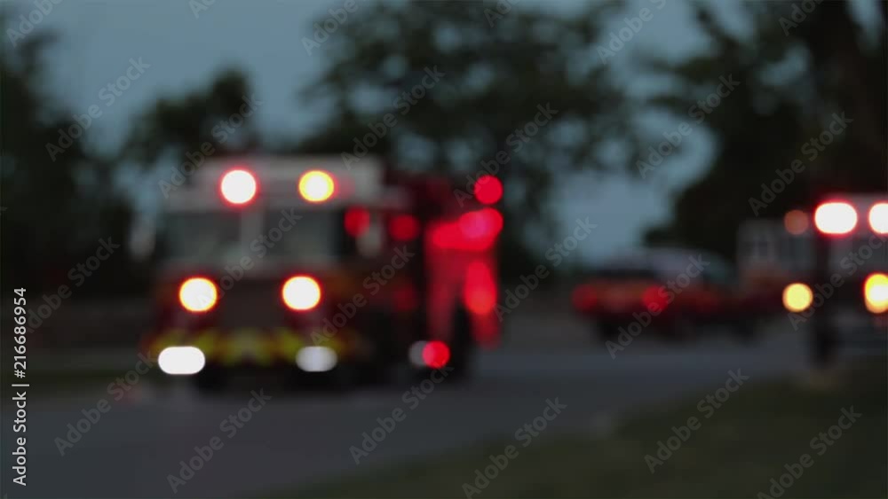 Fire trucks with flashing lights in soft focus at the scene of an urban ...
