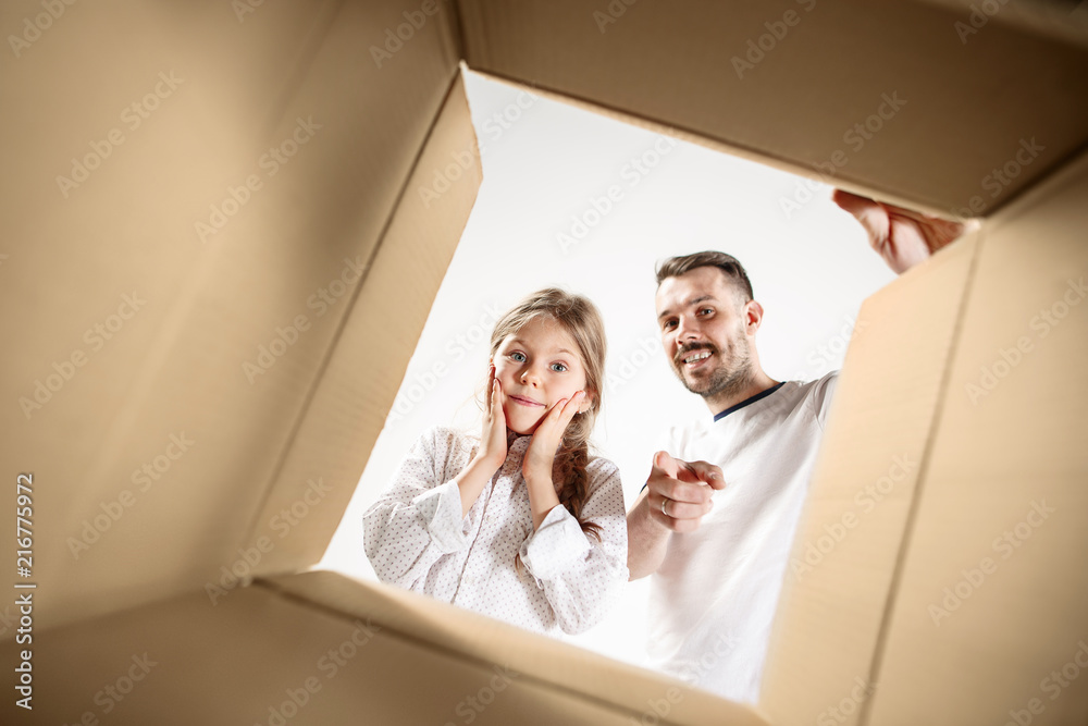 The surprised dad with daughter unpacking, opening carton box and ...