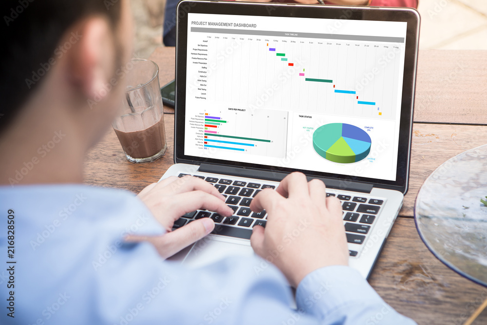 Young man working with excel project dashboard using laptop / computer ...