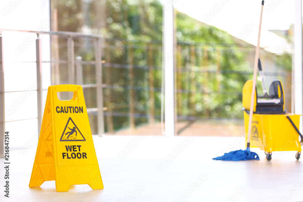 Safety sign with phrase Caution wet floor and mop bucket, indoors ...
