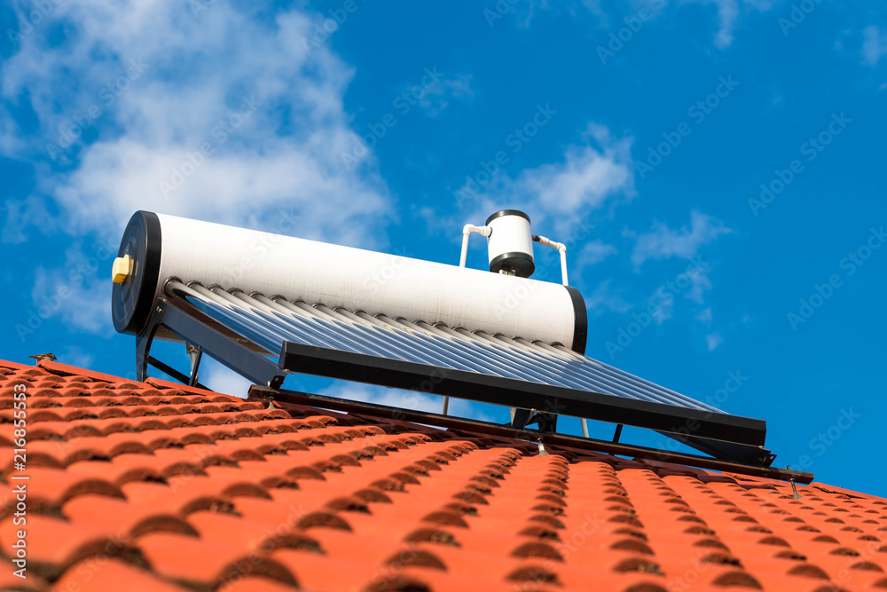 Solar water heater with boiler on roof top, blue sky with white clouds ...