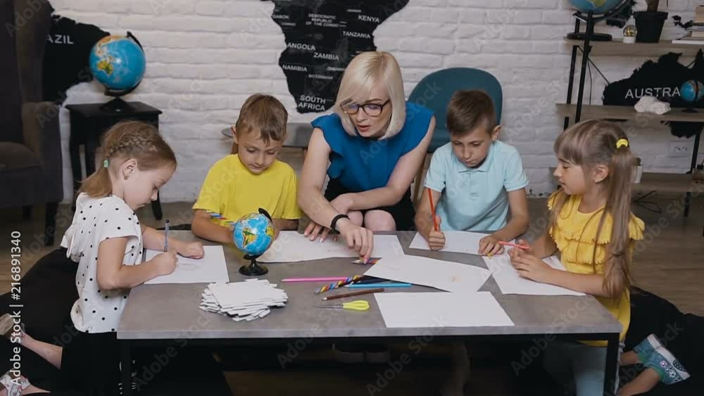 Primary school beautiful children drawing in the classroom with teacher ...