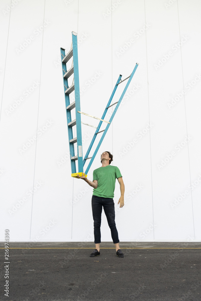 Acrobat balancing ladder upside down in his hand Stock Photo | Adobe Stock