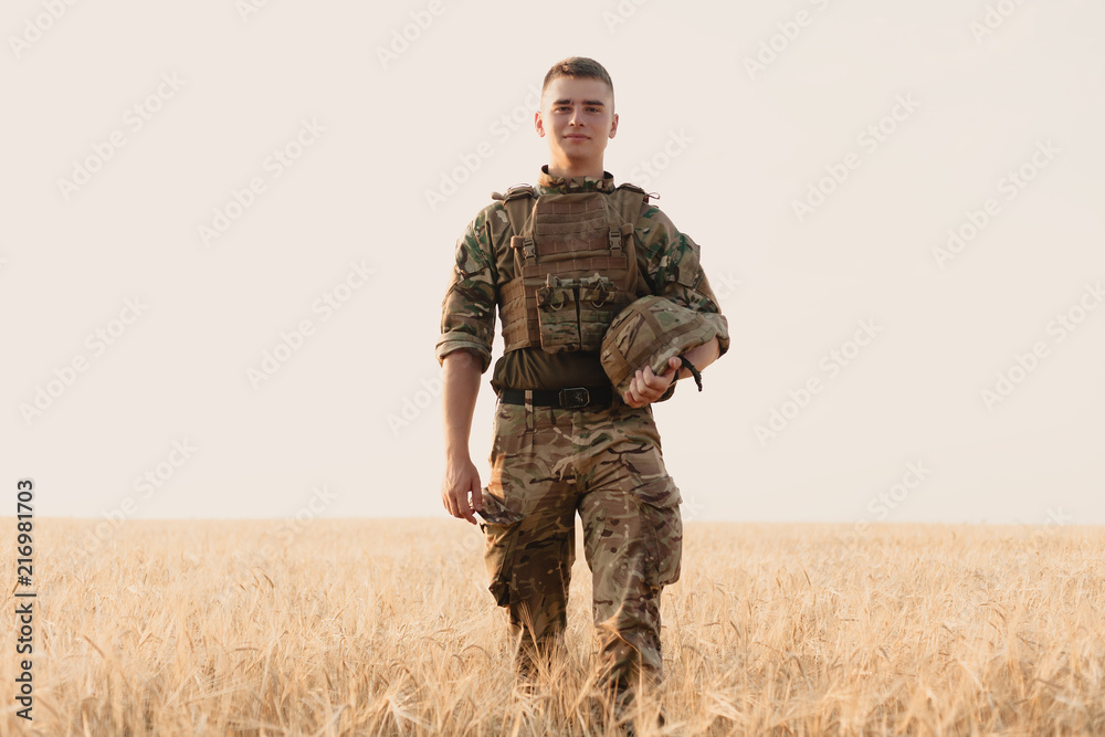 Foto de Soldier man standing against a field. Portrait of happy ...