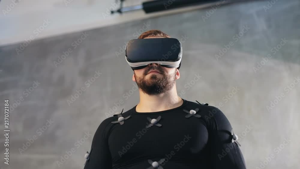 handsome bearded man in black mocap suit with motion sensors using ...