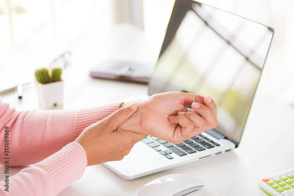 Closeup woman holding her wrist pain from using computer. Office ...