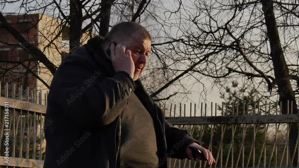 Fat man is nervous talking on phone on city street. Obesity and stress ...