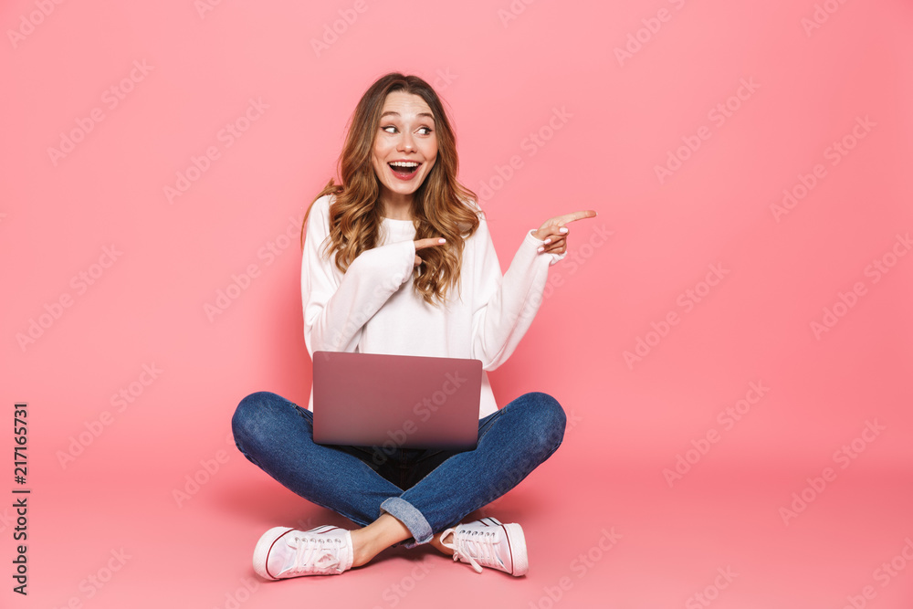 Portrait of a happy young woman sitting with legs crossed Фотографія ...