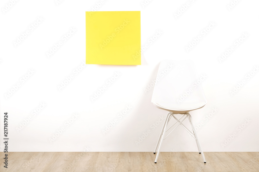 Single empty loft style chair on wooden floor with blank ad poster and ...