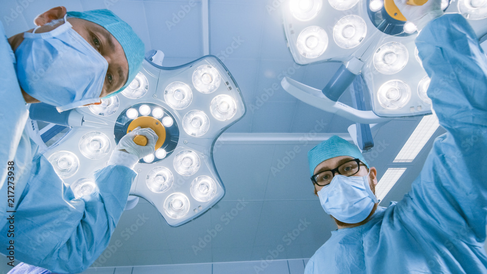 Low Angle Shot POV Patient View: Two Professional Surgeons Turning on ...