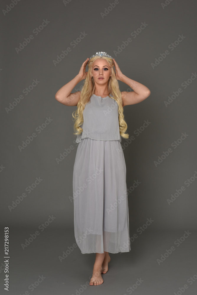 full length portrait of blonde girl wearing crow and grey dress ...