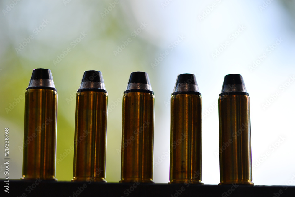 Five isolated revolver bullets on a metal underground. Ammunition for a ...