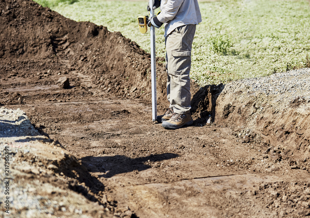 Construction worker measuring the depth of a newly dug trench Stock ...