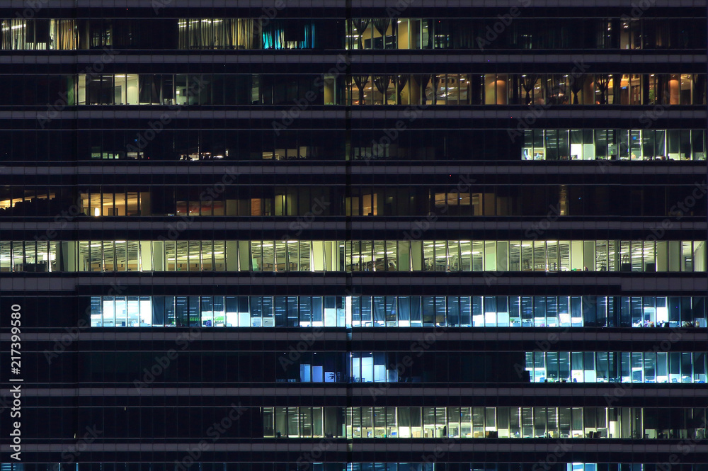 workers in a box. office building light at night. multistory modern ...