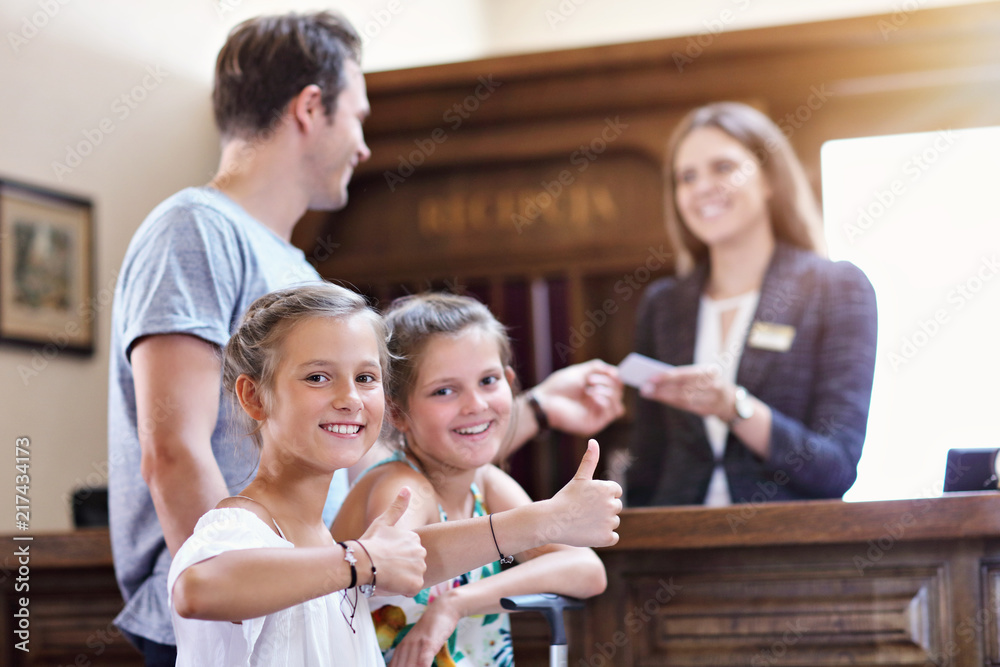 Happy family checking in hotel at reception desk Stock Photo | Adobe Stock
