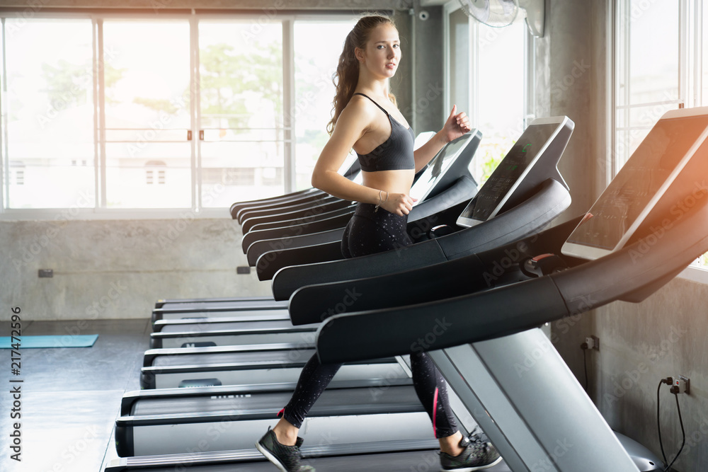 Cute young woman exercising on treadmill at a gym.Active young woman ...