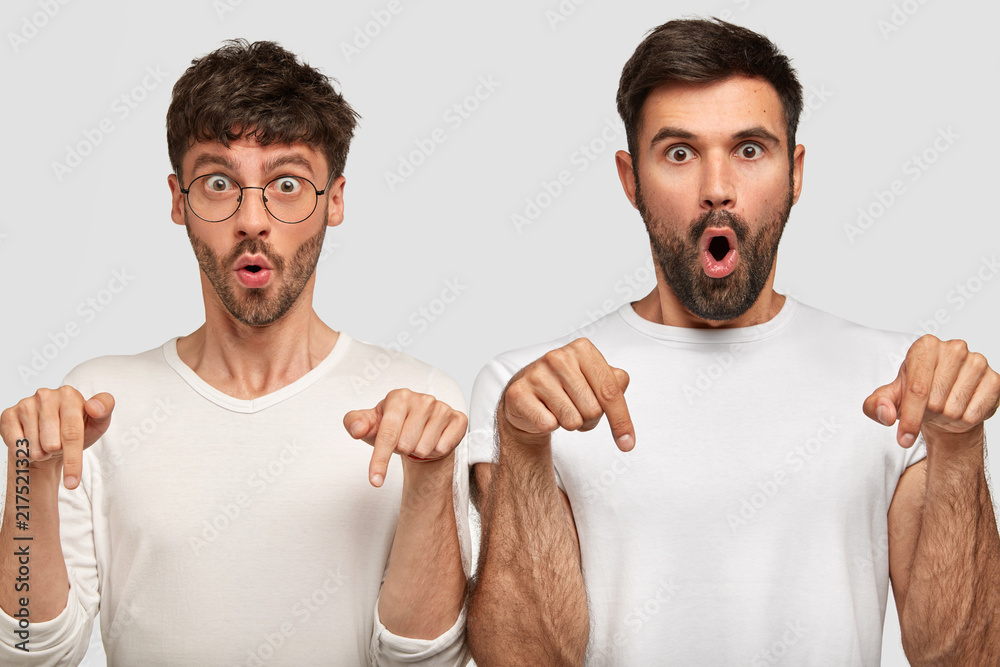 Two surprirsed men with scared puzzled facial expressions point ...