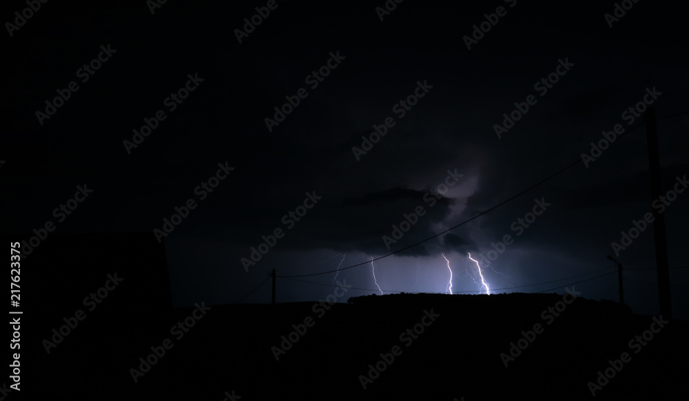 Single lightning strike in nature in a field with colours of white and ...