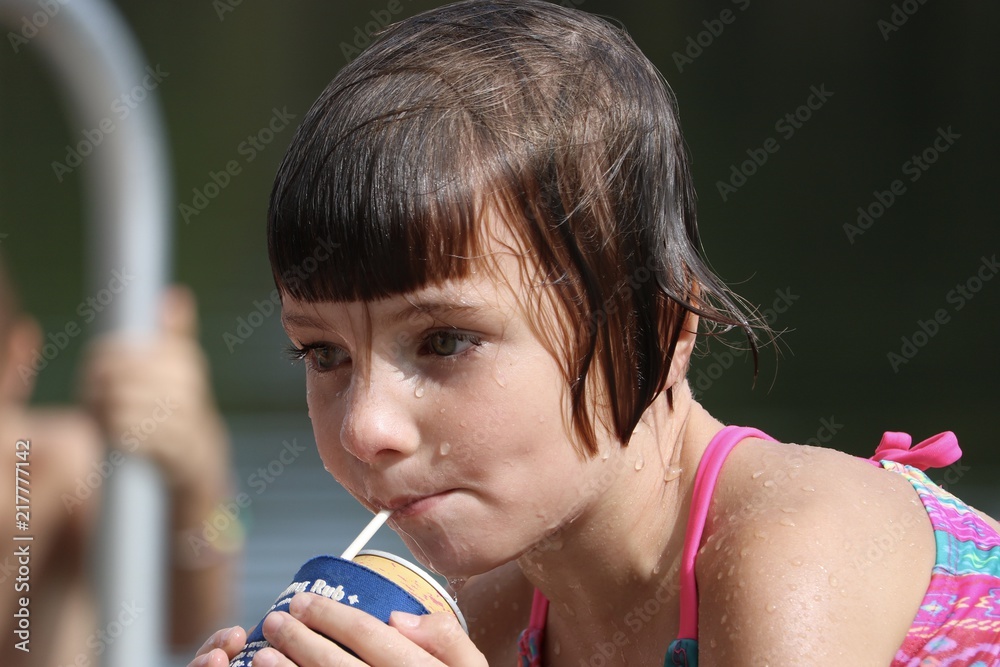 Wet young child having a drink while taking a break from swimming Stock ...