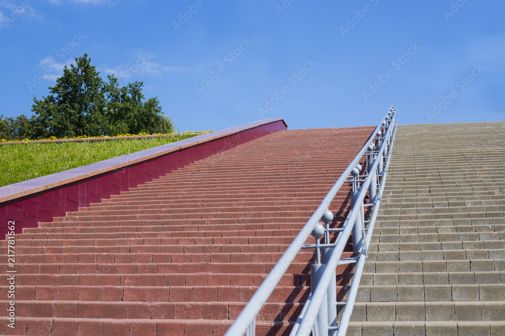 The staircase is red, with a lot of steps and railings, rises up along ...