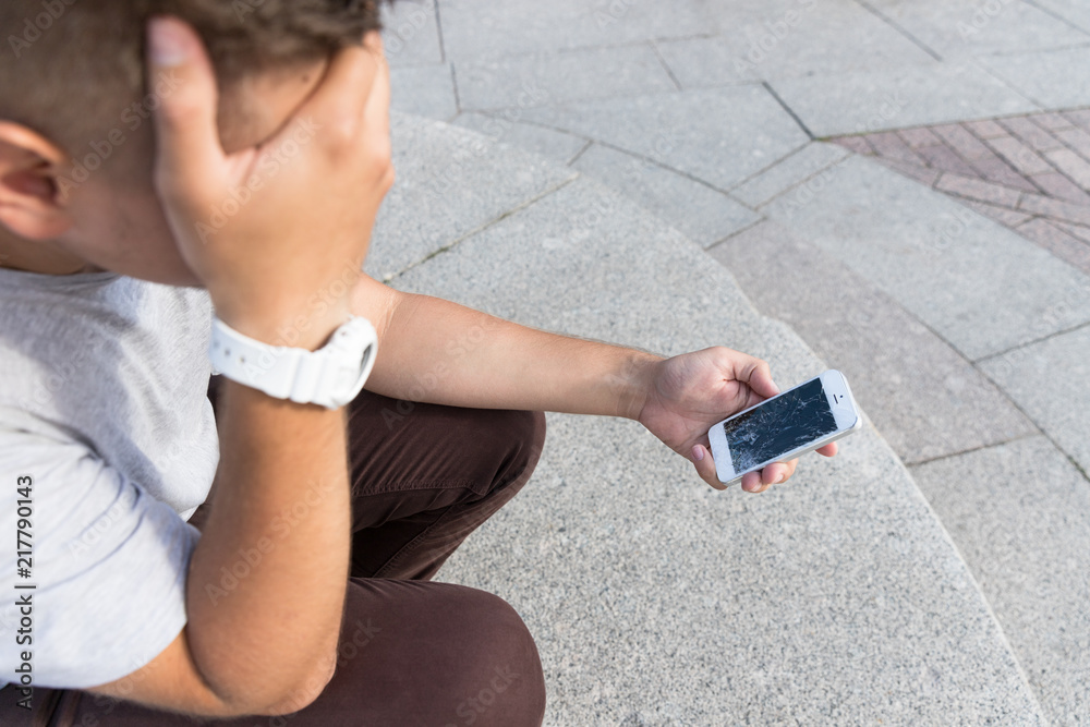 Sad Caucasian male holding broken mobile smartphone after drop, makes ...