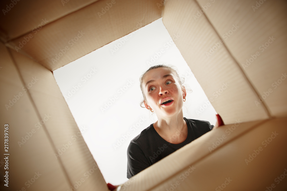 The surprised woman opening box and looking inside. The package ...