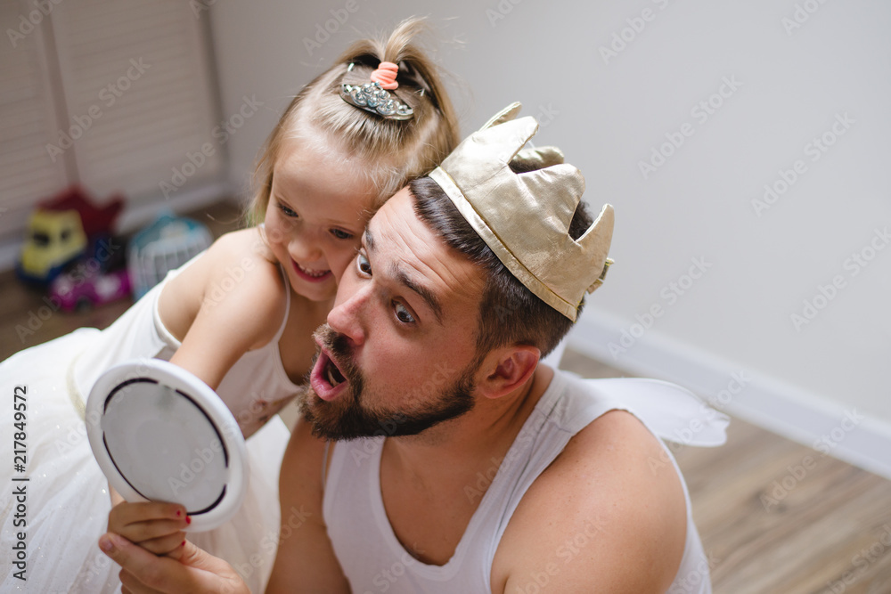 Little daughter and father have fun, dressing in princess costume ...