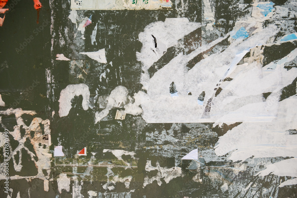 Urban billboard wall with torn and ragged glued paper posters and ...