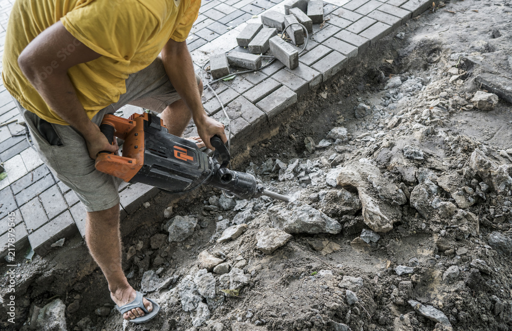 Workers use Electric Concrete Breaker. Male worker repairing driveway ...
