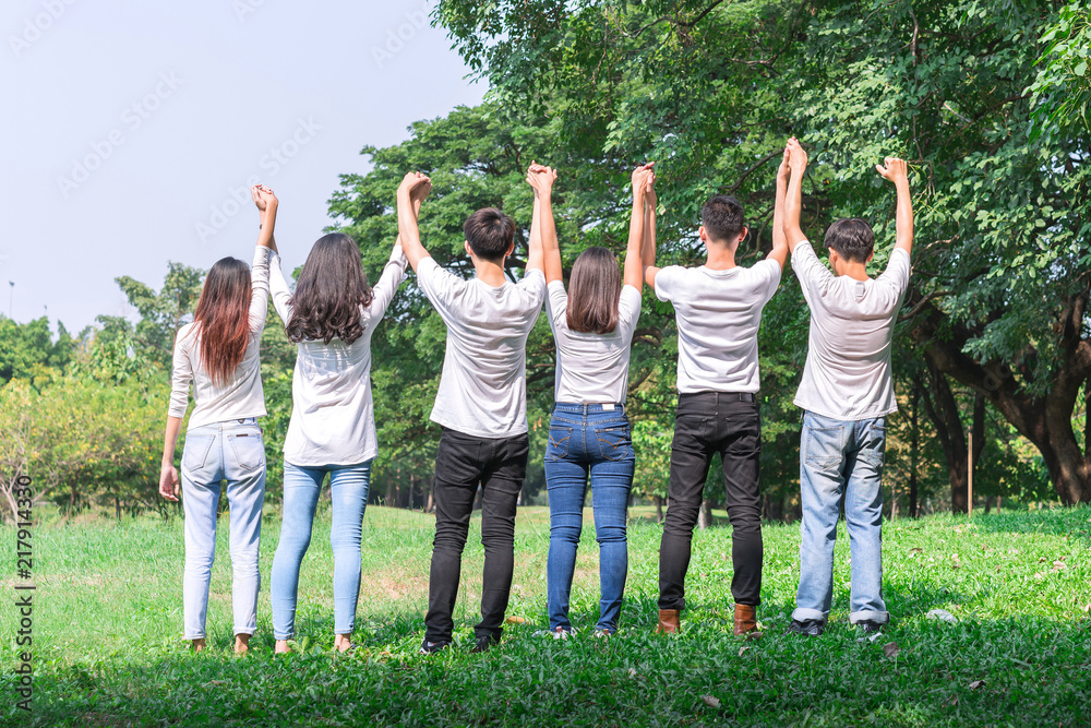 Six people standing and holding hands in the park forest at outdoors ...