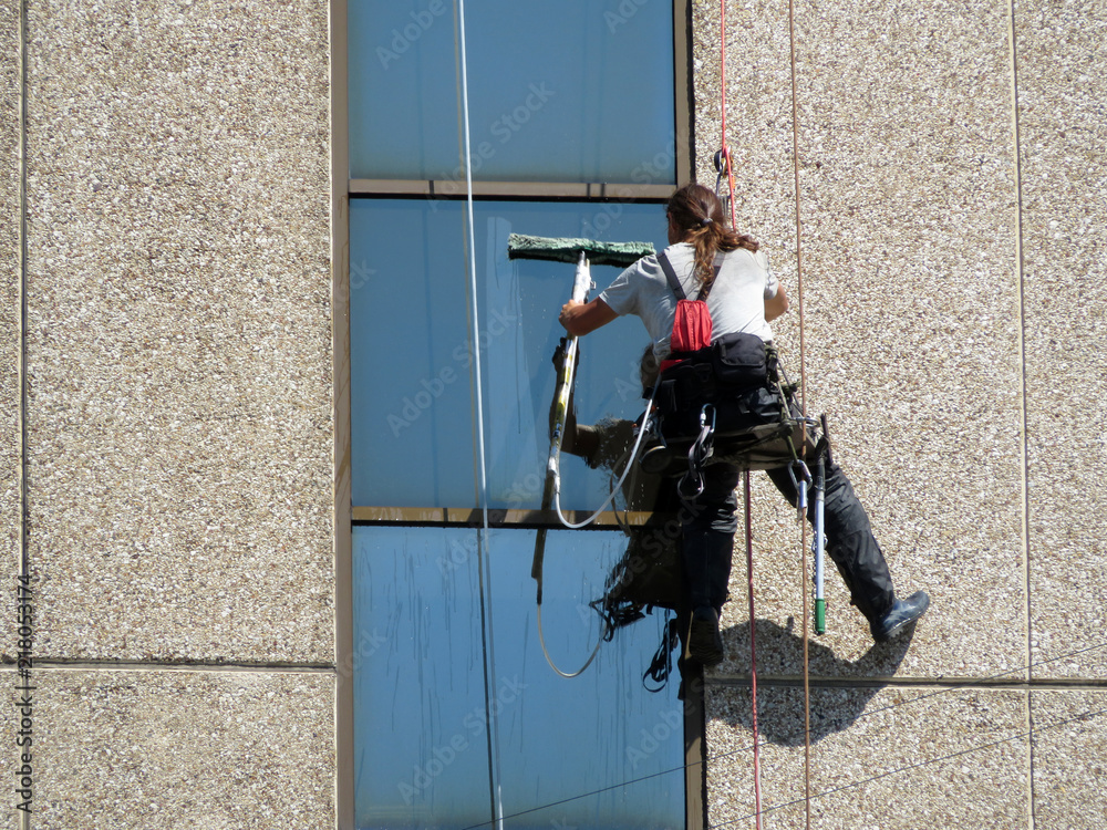 Windows cleaner on the high rise building facade. Worker washes the ...