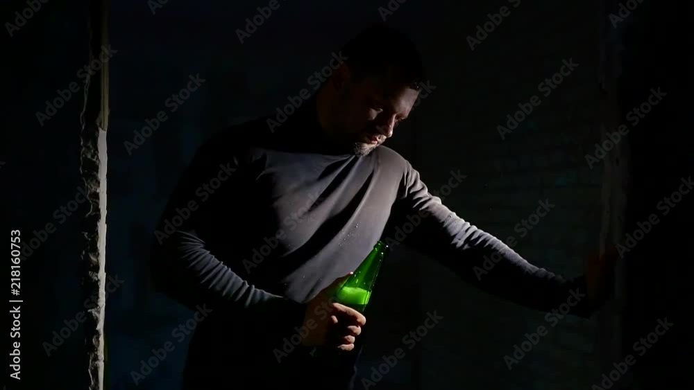 drunk alcoholic man standing in a ruined building in the dark and ...