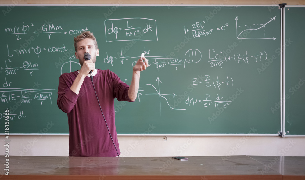 young professor teacher with microphone standing near the blackboard ...