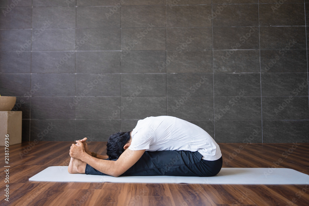 Experienced yogi doing seated forward bend yoga pose in gym. Man ...