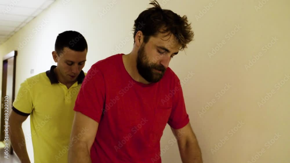 Portrait of young disabled man walking holding a walking frame through ...