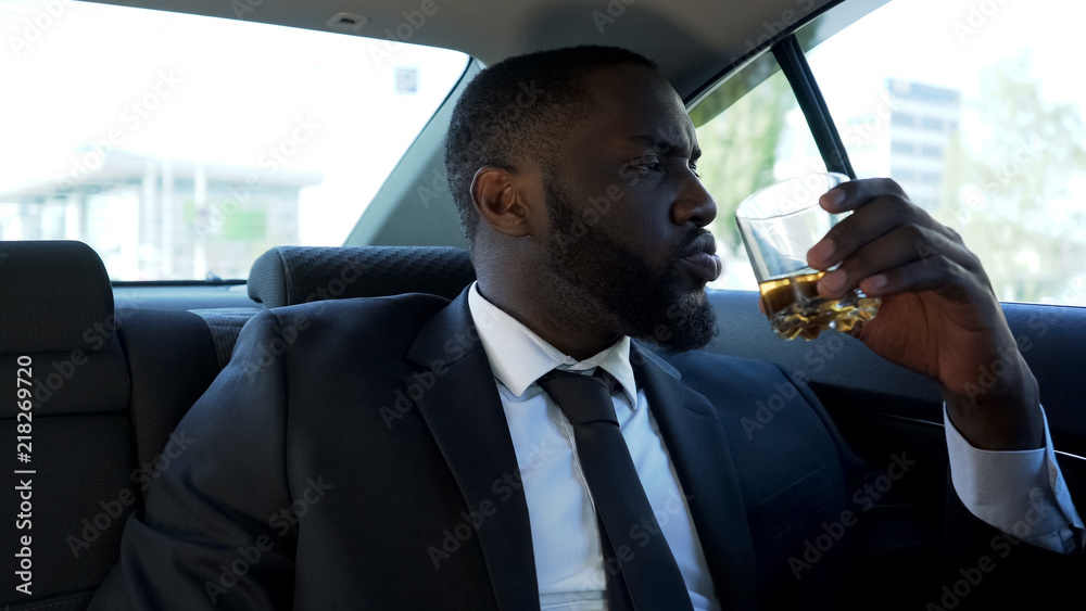 Self-confident rich man drinking alcohol in car, luxury lifestyle ...