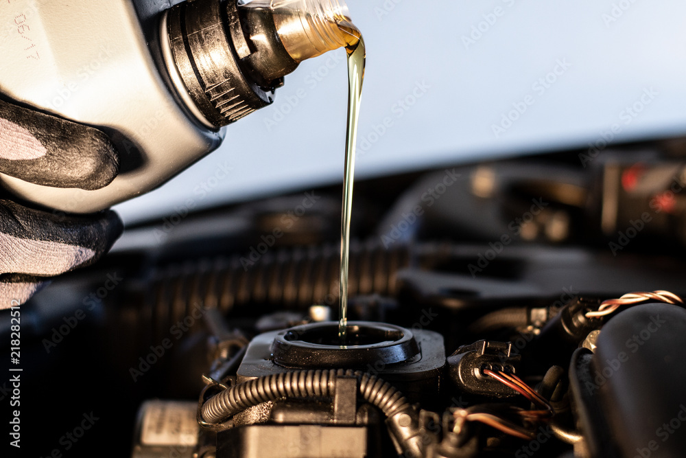 Mechanic fills up the engine with engine oil Stock Photo | Adobe Stock
