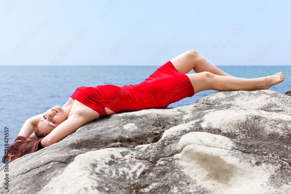 Girl in red dress lying on white rock Stock Photo | Adobe Stock