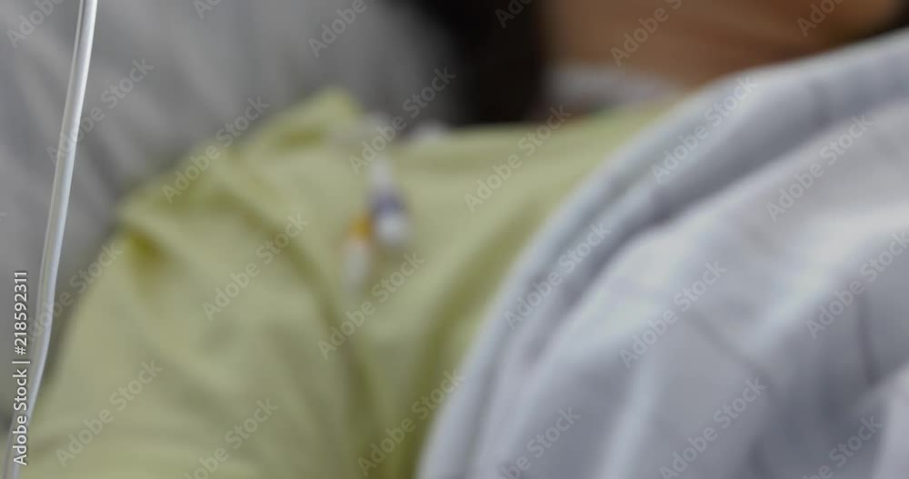 A woman lies in a post-operative room on a hospital bed. The catheter ...